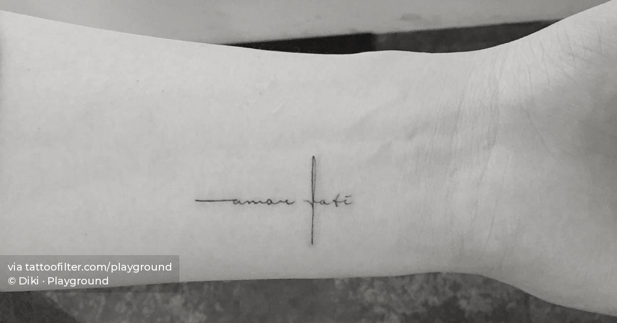 "Amor fati" lettering cross tattooed on the wrist.