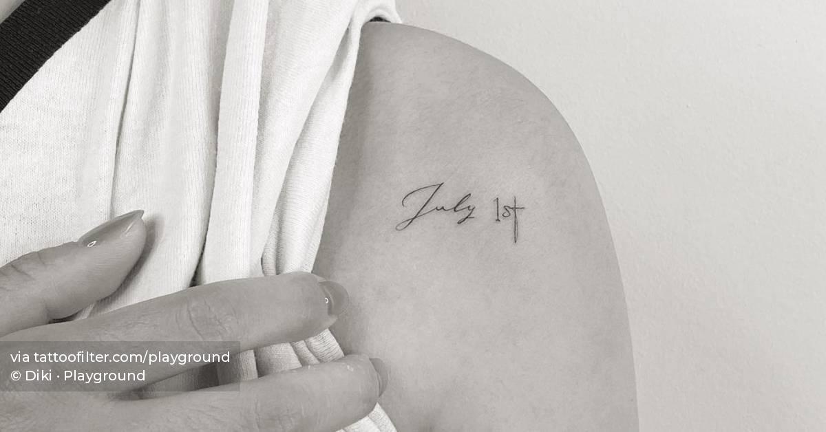 "July 1st" lettering tattoo located on the shoulder.