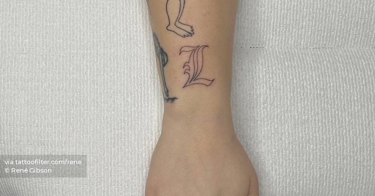 Letter "L" tattoo located on the wrist.