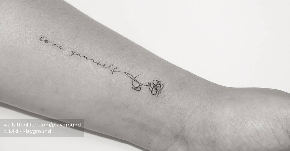 "Love yourself" and flower tattooed on the wrist.