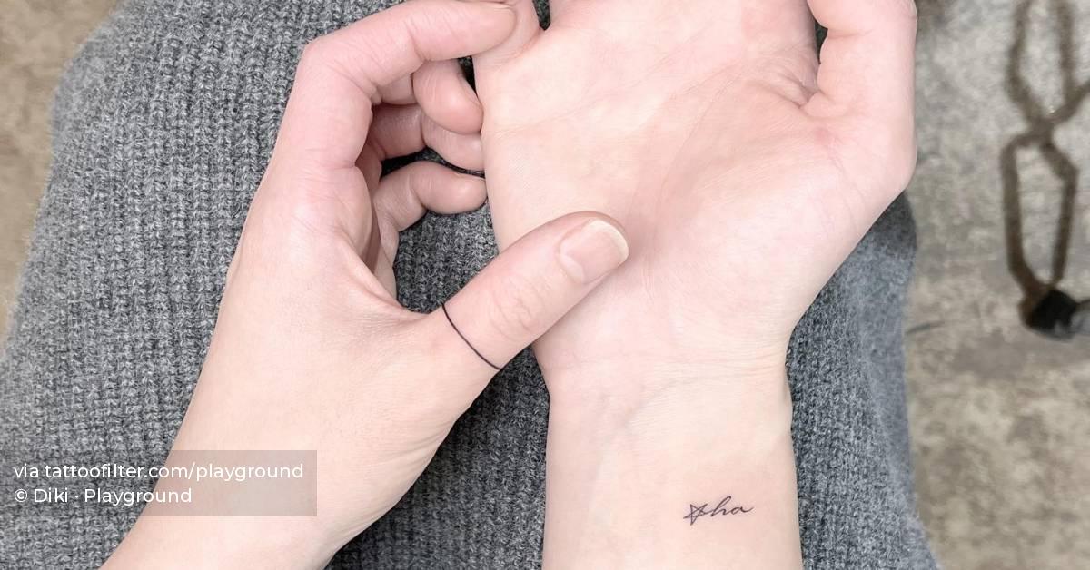 Star and initials tattoo placed on the wrist.