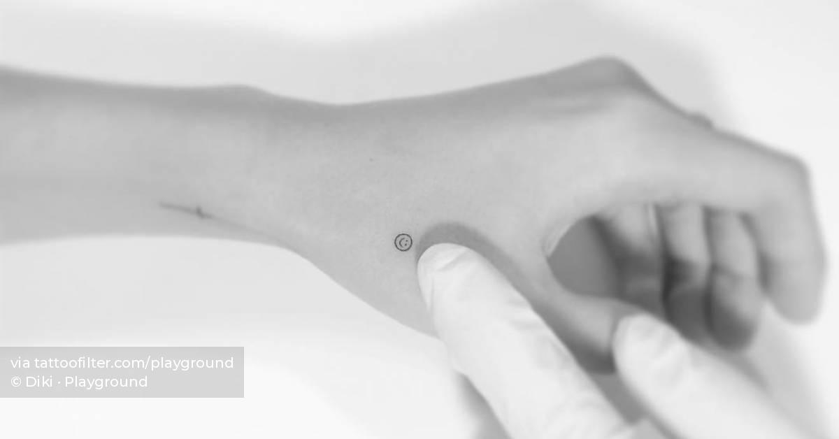 Micro smiley face tattoo placed on the hand,