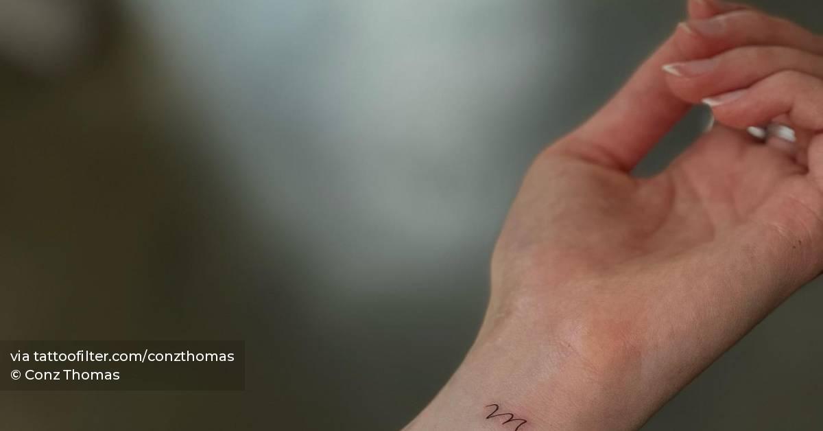 Minimalistic letter "M" tattoo placed on the wrist.