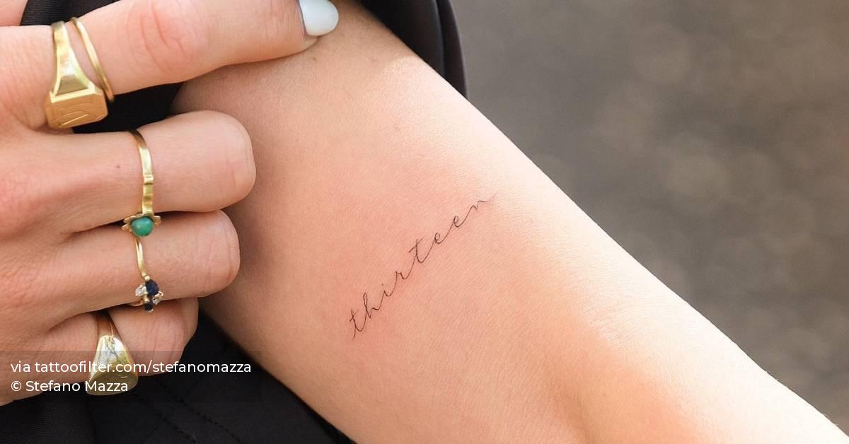 Tattoo that says "thirteen" located on the upper arm.