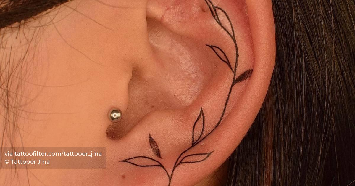 Leaves tattoo located on the ear, minimalistic style.
