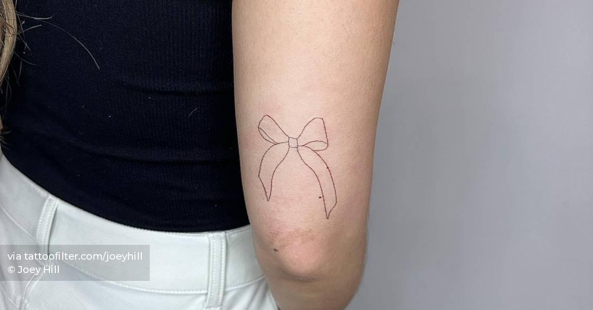 Fine line style ribbon tattoo located on the tricep.