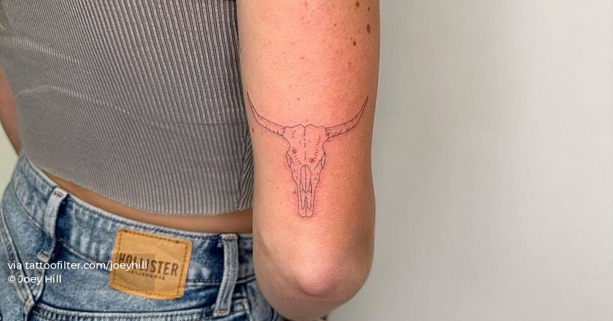 Fine line style bull skull tattoo placed on the tricep.