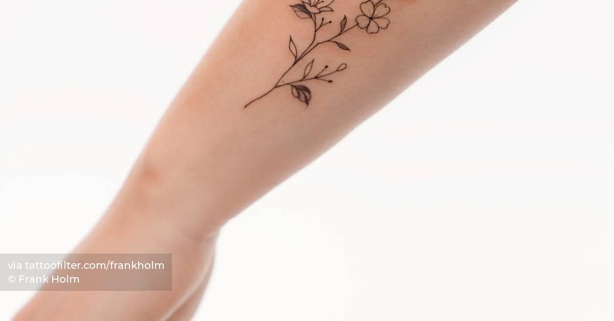 Fine line style lily flowers tattooed on the wrist.