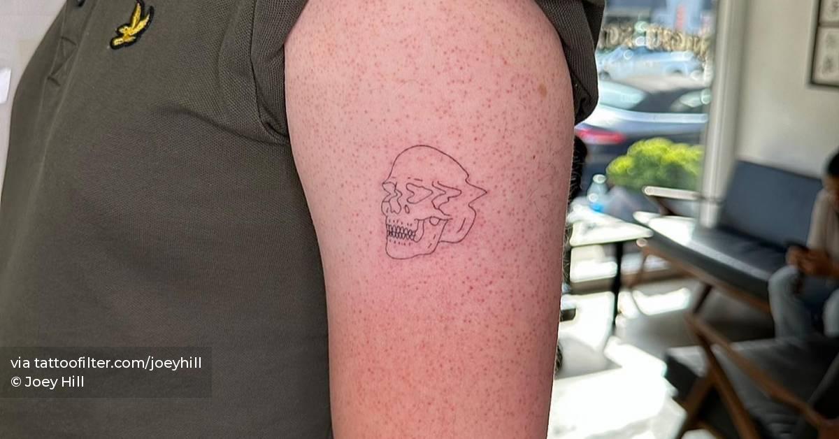 Fine line skull tattoo done on the upper arm.
