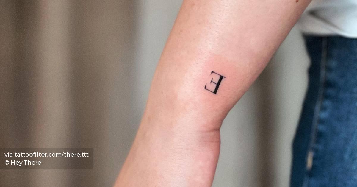 Minimalistic tattoo of the letter "E" located on the