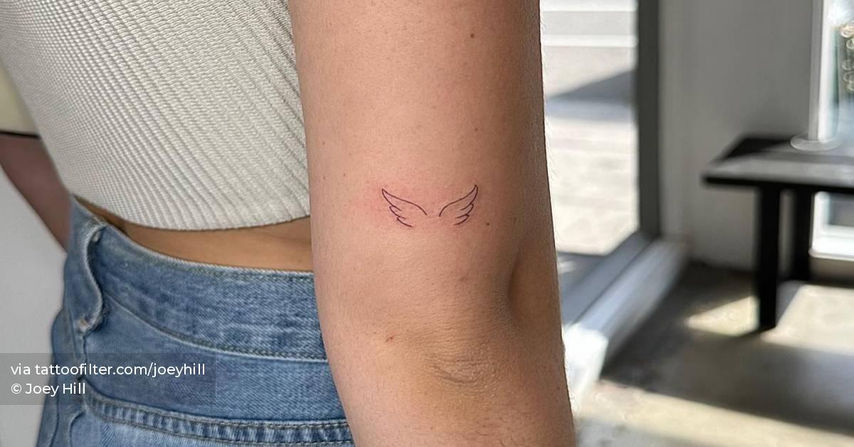 Angel wings tattoo located on the tricep, fine line