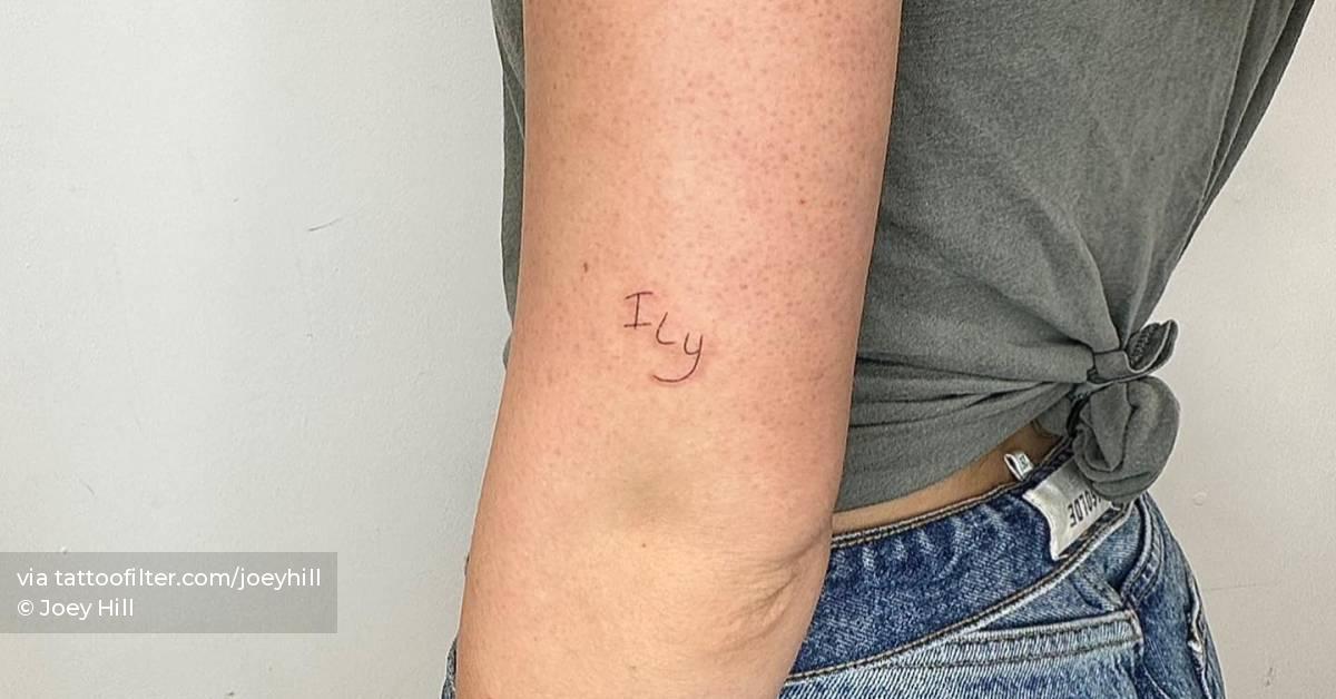 "ILY" lettering tattoo handwritten on the upper arm.
