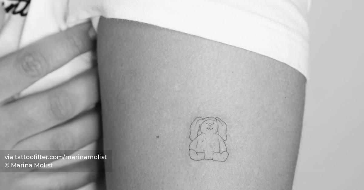 Fine line style teddy bunny tattooed on the upper arm.