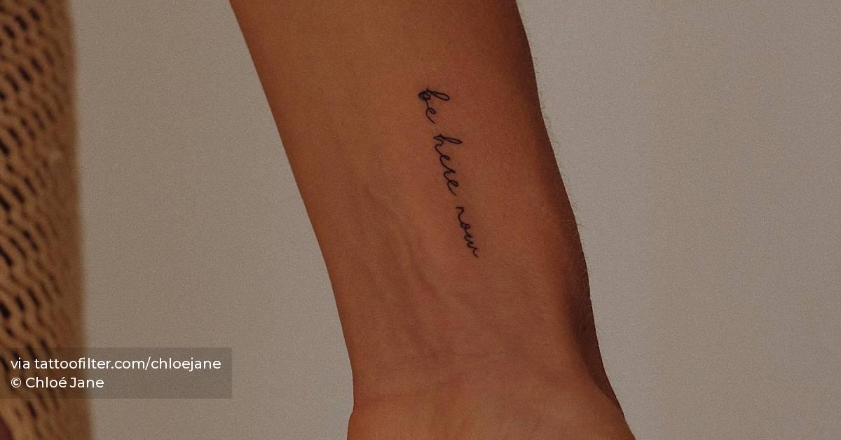 "Be here now" lettering tattoo placed on the wrist.