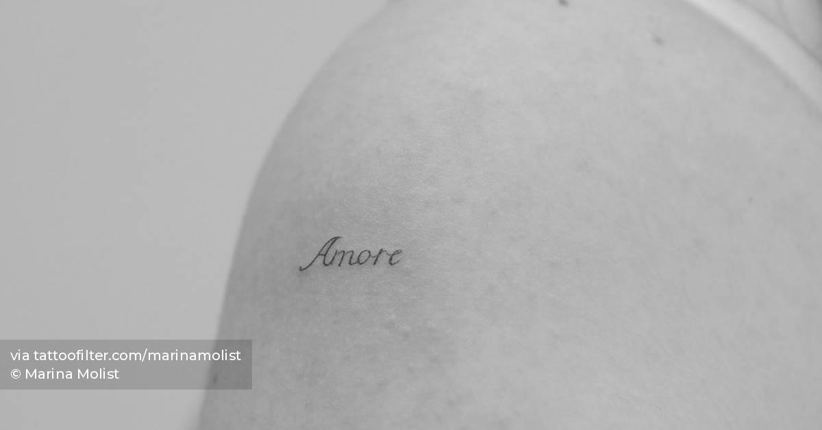 "Amore" lettering tattoo placed on the shoulder.