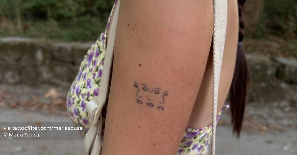 Minimalistic faces tattooed on the upper arm.