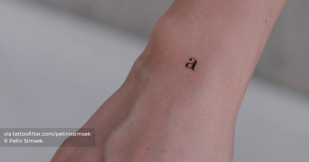 Tiny letter "a" tattoo placed on the wrist.
