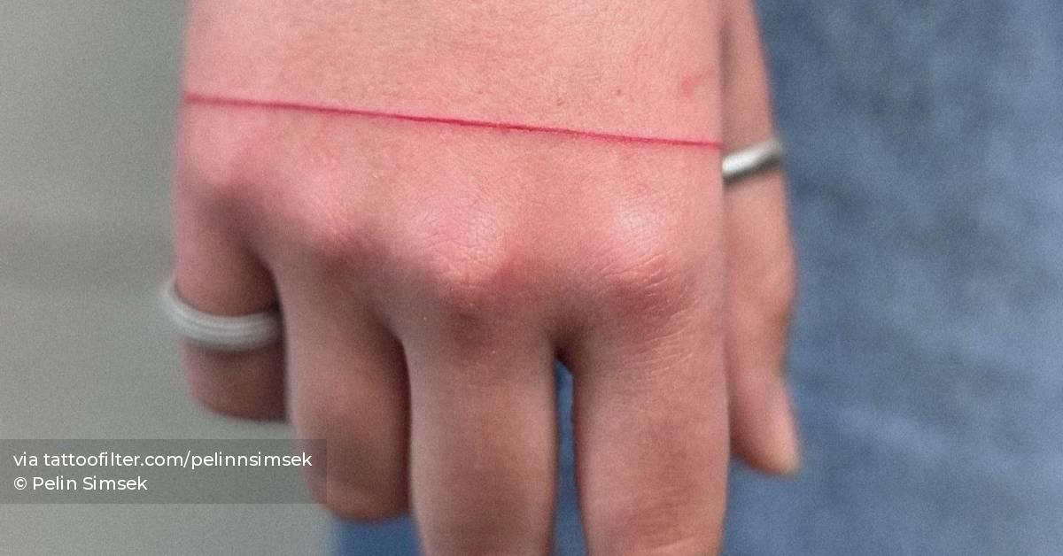 Red minimalistic line tattoo done on the hand.