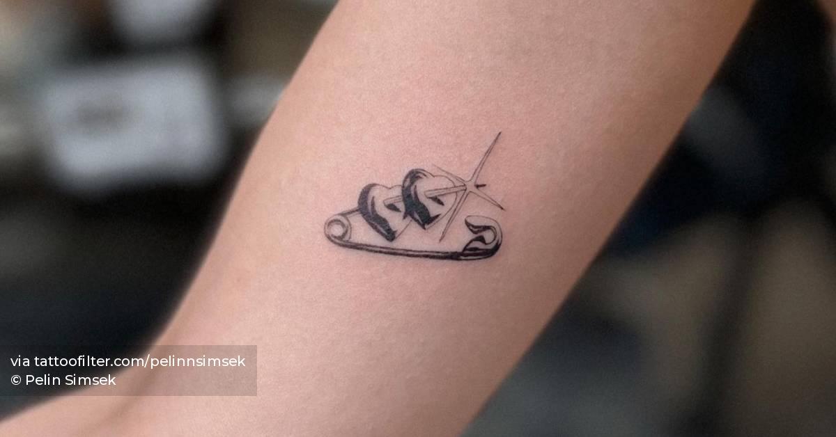 Safety pin and hearts tattoo located on the inner arm.