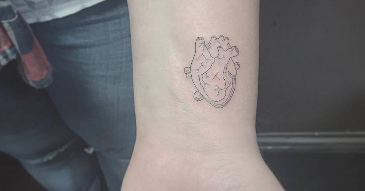 Fine line style heart tattoo on the left inner wrist.