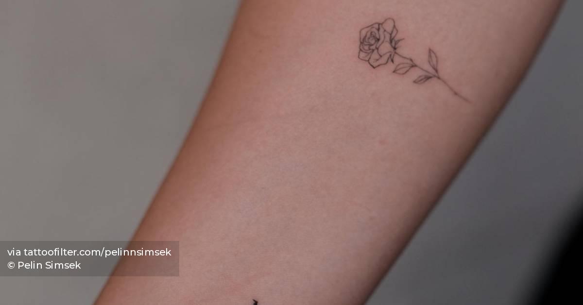 Fine line rose and letter "M" tattoo located on the