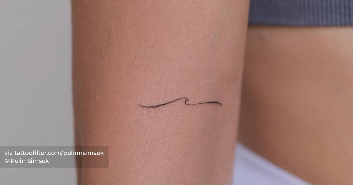 Minimalistic style wave tattoo placed on the upper arm.