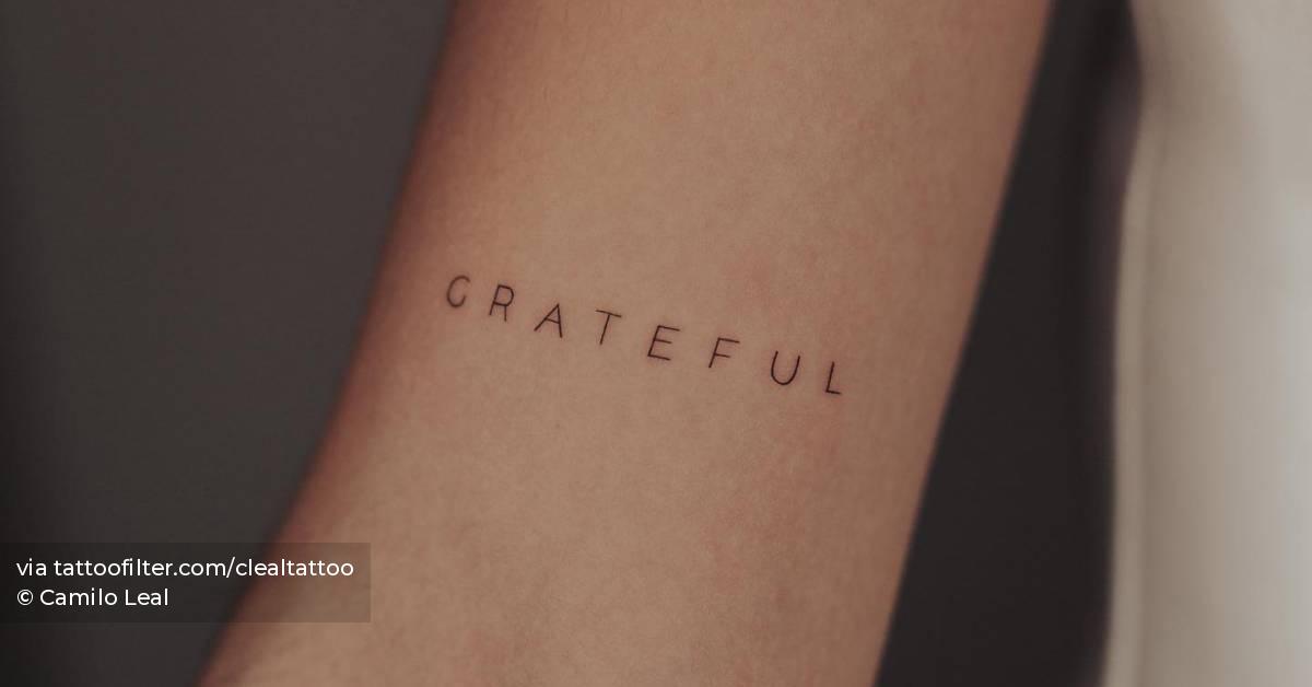 Tattoo that says "grateful" handwritten on the bicep.