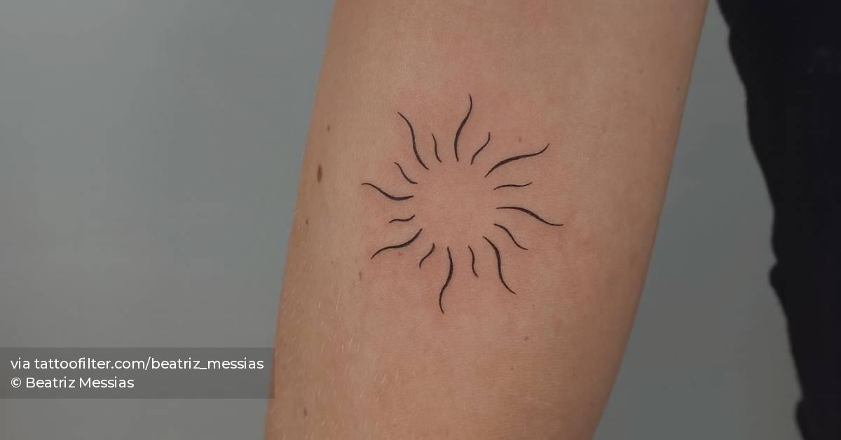 Minimalistic style sun tattoo located on the upper arm.