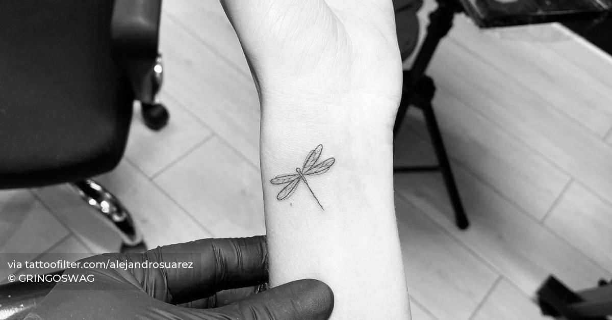 Fine line style dragonfly tattoo located on the wrist.