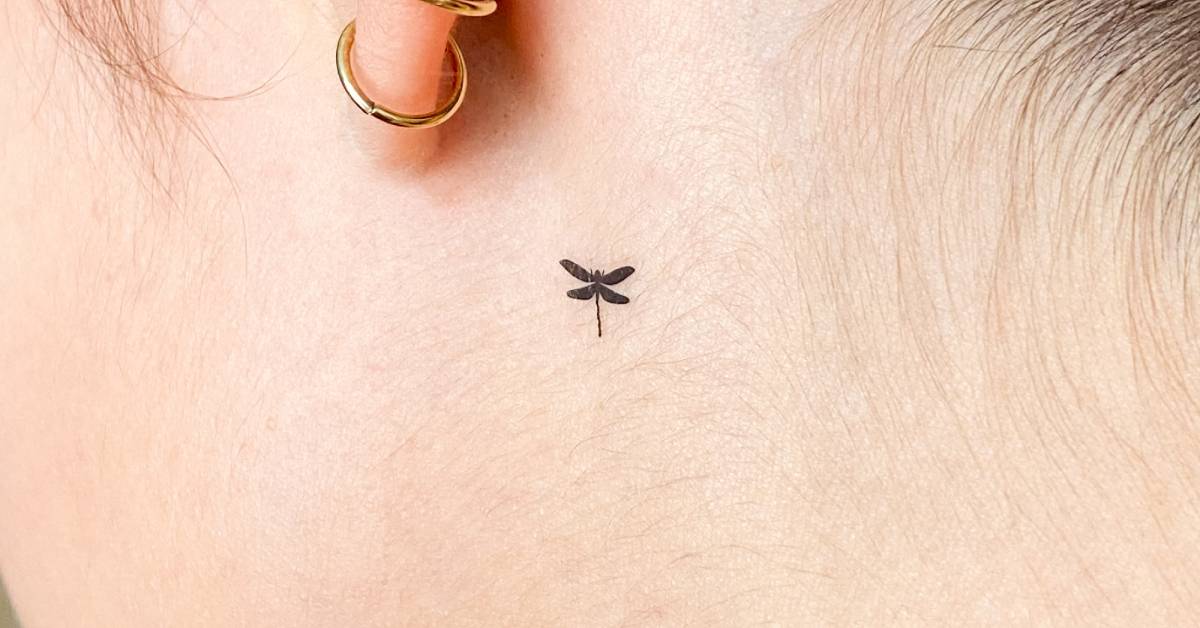 Cute tiny dragonfly temporary tattoo located behind the