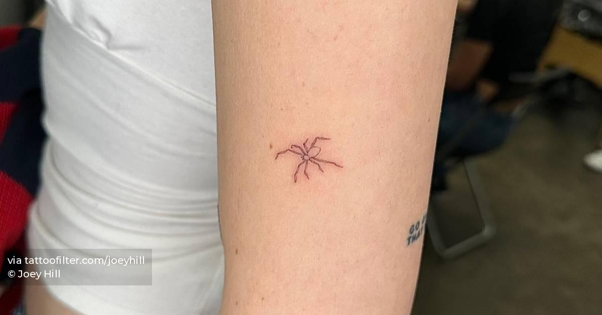 Minimalistic style spider tattoo placed on the upper