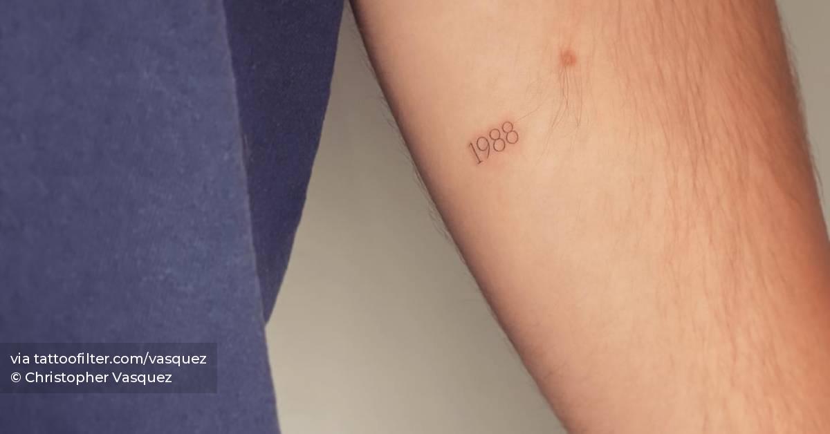 "1988" lettering tattoo located on them inner forearm.