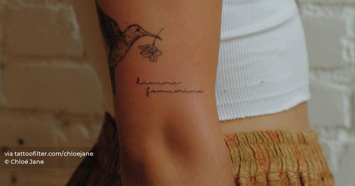 "Divine feminine" lettering tattoo located on the upper