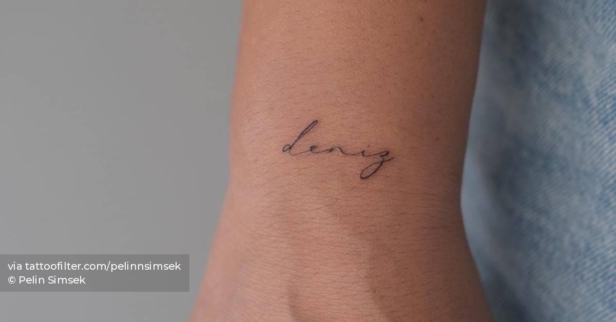 Tattoo of the name "Deniz" handwritten on the wrist.