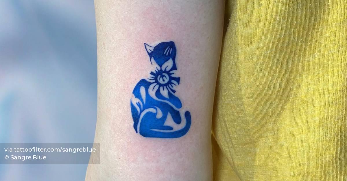 Porcelain cat in blue ink tattooed on the tricep.