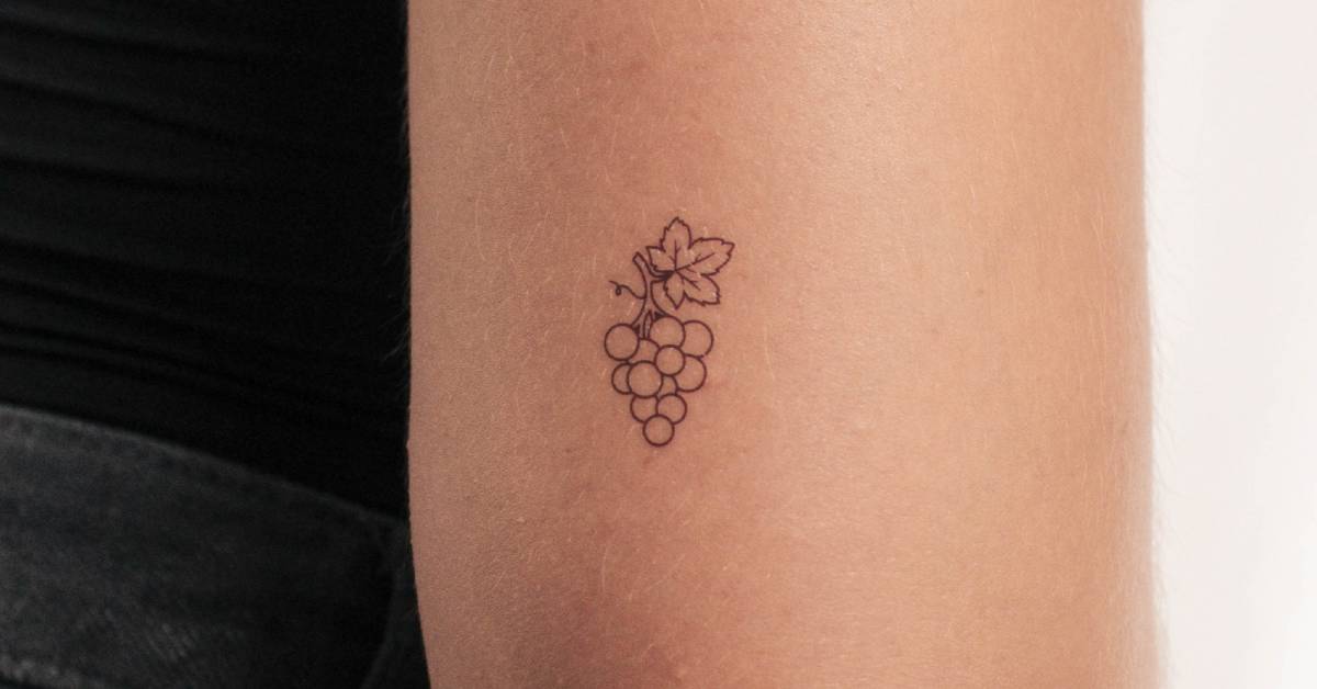 Fine line style grapes tattoo located on tricep.