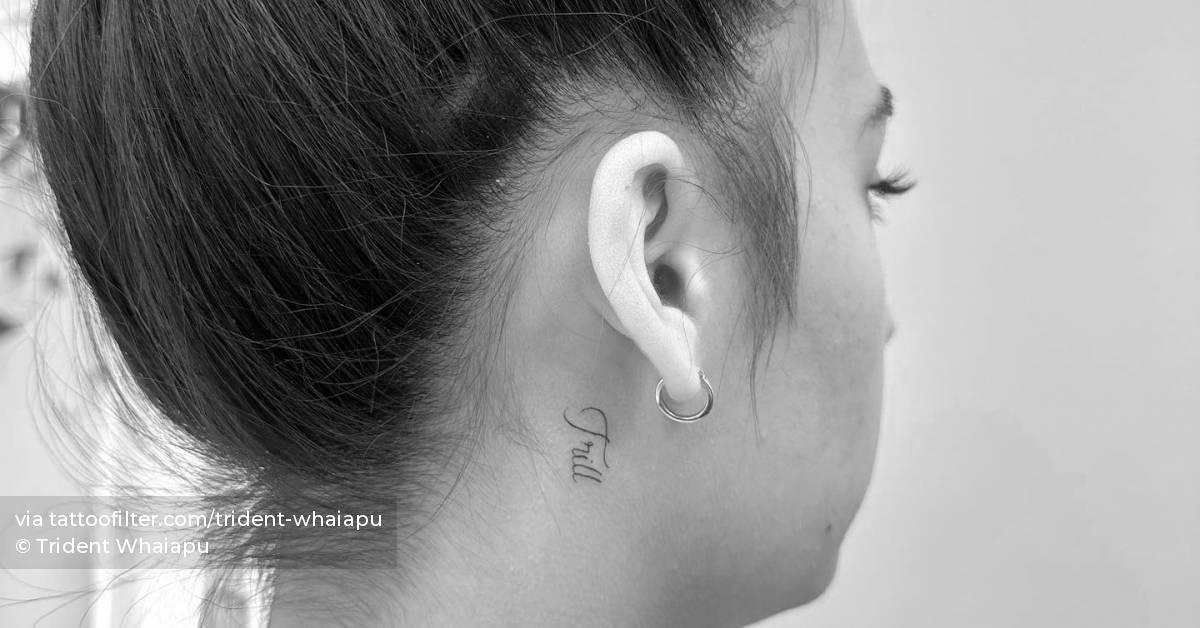 "Trill" lettering tattoo placed behind the ear.
