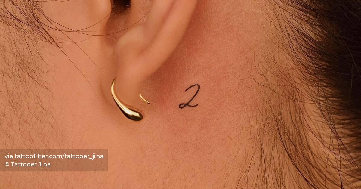 Tiny tattoo of the number "2" located behind the ear.