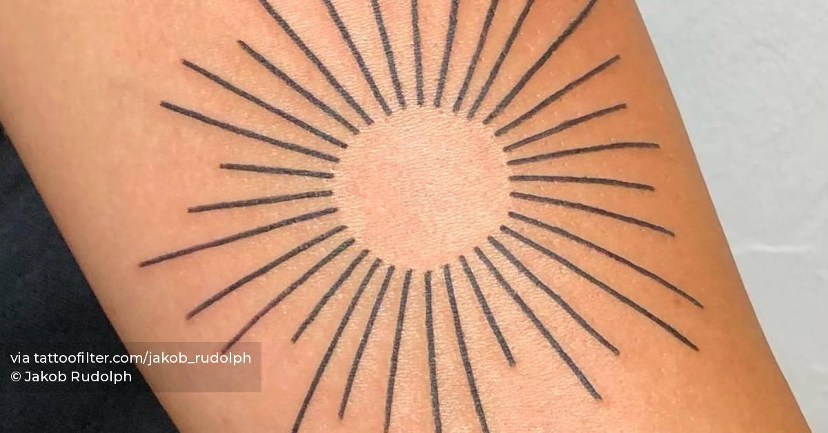 Line art sun tattoo located on the inner forearm.