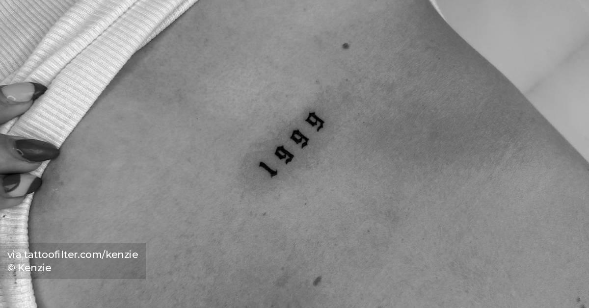 "1999" lettering tattoo done on the stomach.