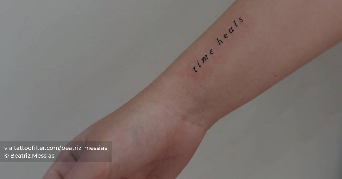 "Time heals" lettering tattoo located on the wrist.