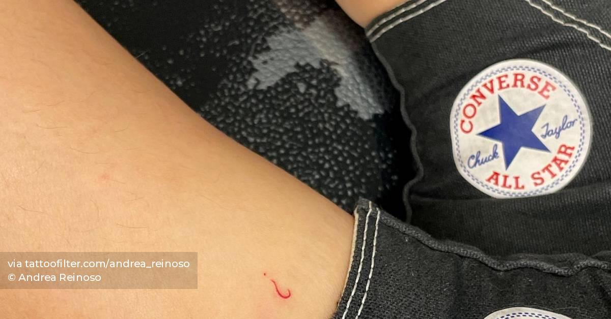 Tiny red question mark tattoo placed on the ankle.