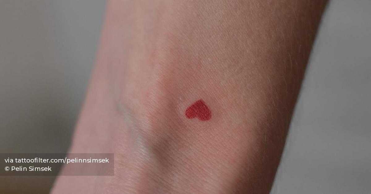 Minimalistic style red heart tattoo located on the