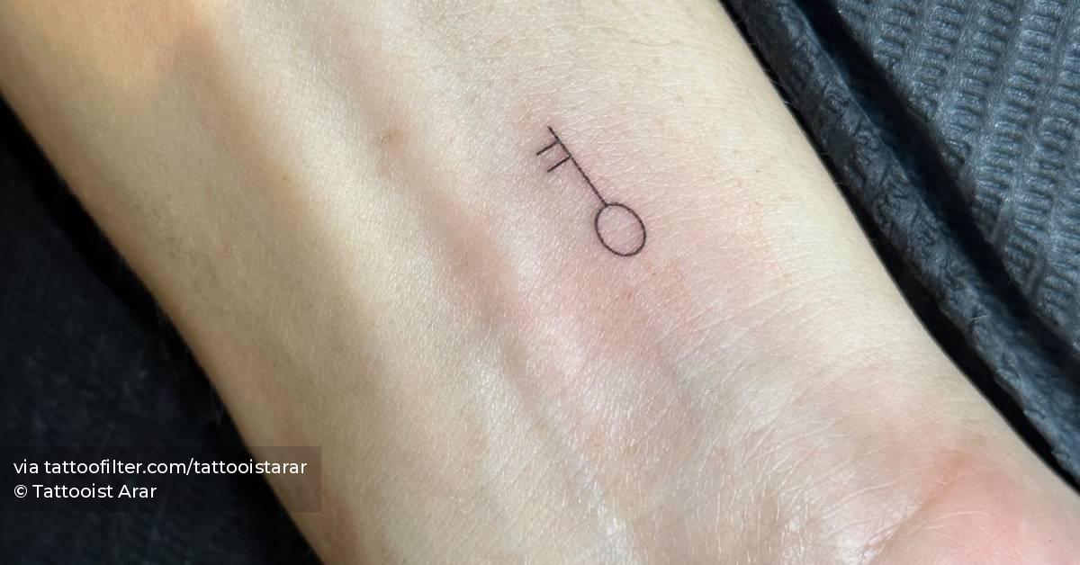 Minimalistic little key tattoo placed on the wrist.