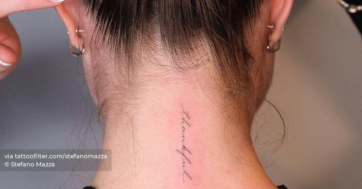 Tattoo of the word "thankful" handwritten on the back