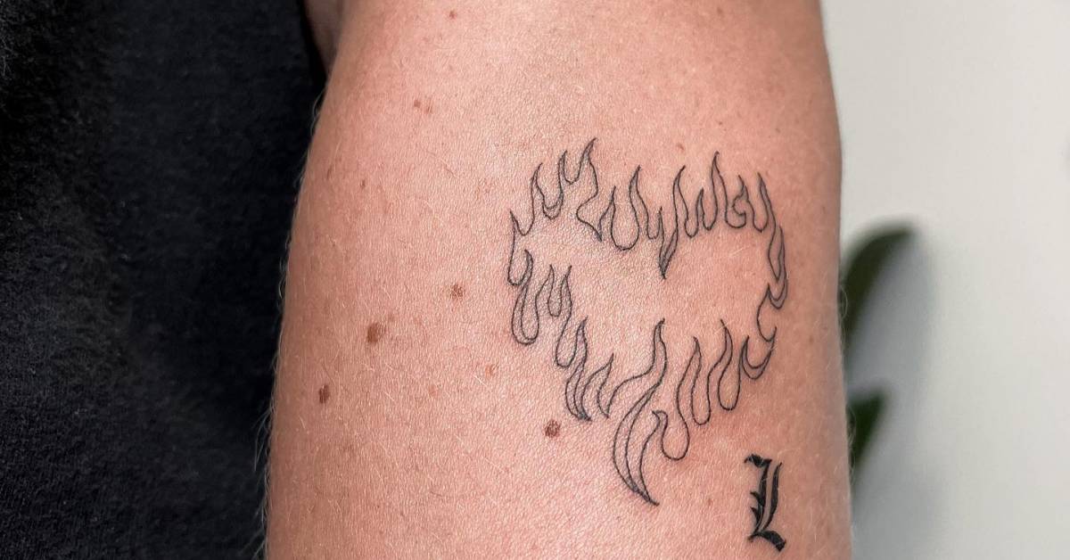 Flaming heart and letter "L" tattoo located on the