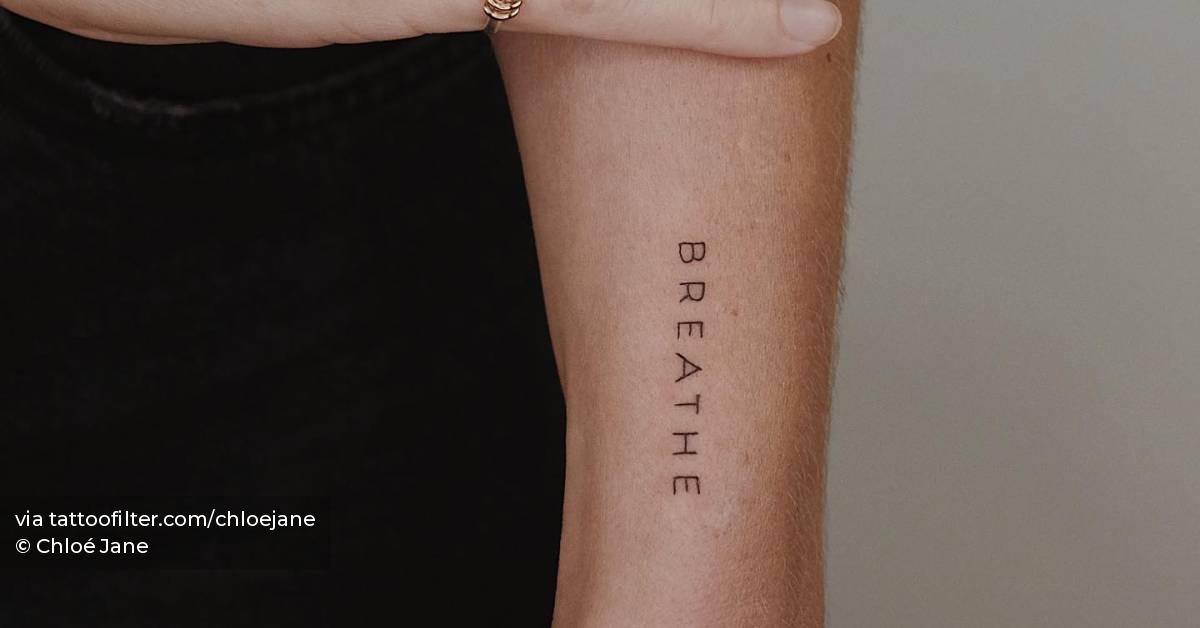 Tattoo of the word "breathe" handwritten on the wrist.