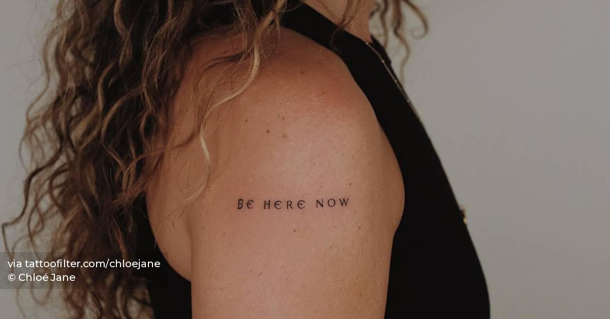 Lettering tattoo that says "be here now" placed on the