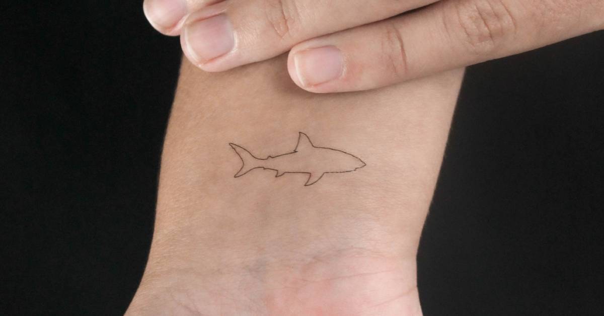 Fine line shark temporary tattoo located on the wrist.