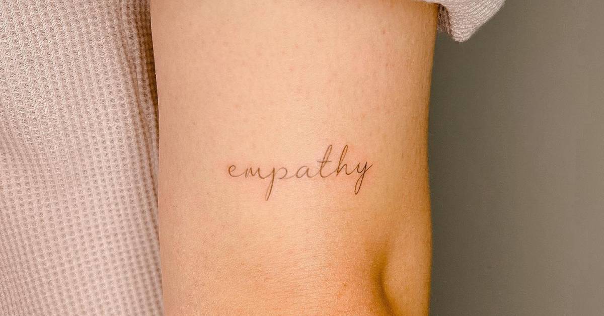 Tattoo of the word "empathy" handwritten on the tricep.